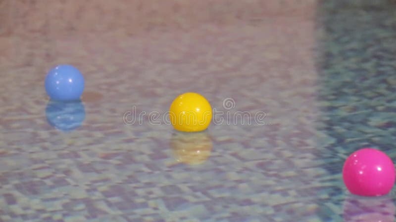 Red, Yellow and Blue Plastic Balls Swing on Light Waves in the Pool ...
