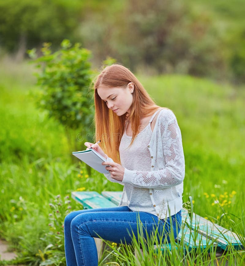Girl with Pen Writing on Notebook on Grass Outside Stock Photo - Image ...