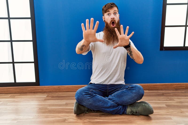 Redhead Man with Long Beard Sitting on the Floor at Empty Room Afraid ...