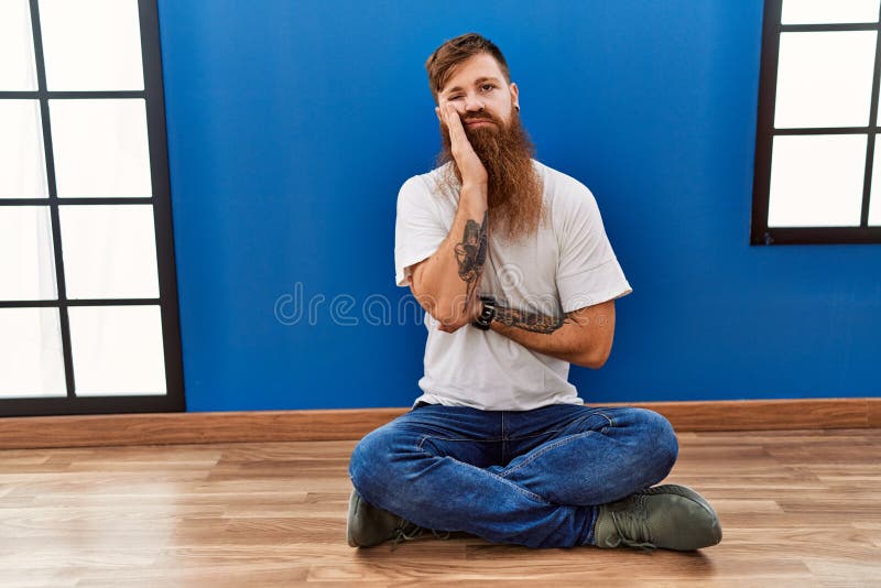 Redhead Man with Long Beard Sitting on the Floor at Empty Room Thinking ...