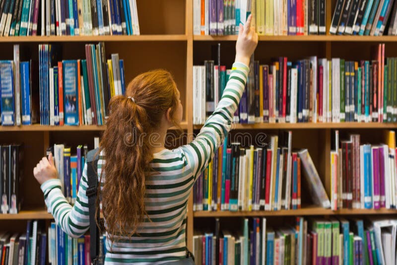 Redhead Student Taking Book from Top Shelf in Library Stock Image ...