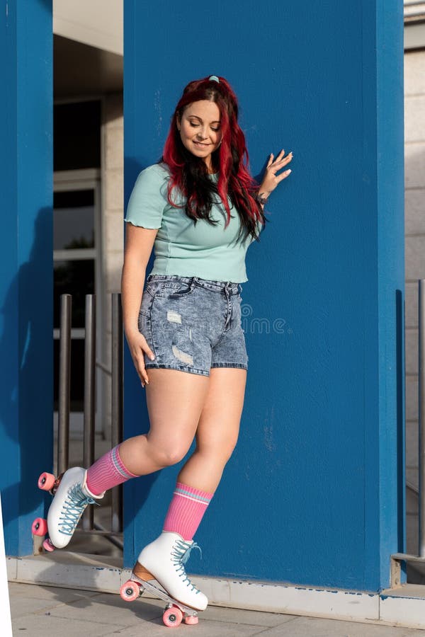 Pretty Redheaded Woman on Four-wheeled Roller Skates Posing on a Wall ...