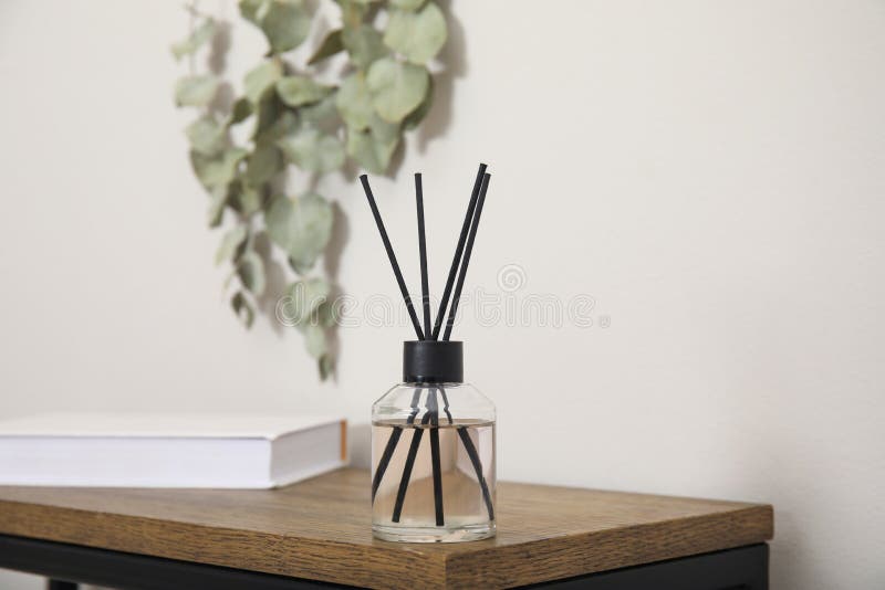 Reed Diffuser and Book on Wooden Table Near White Wall Stock Photo ...