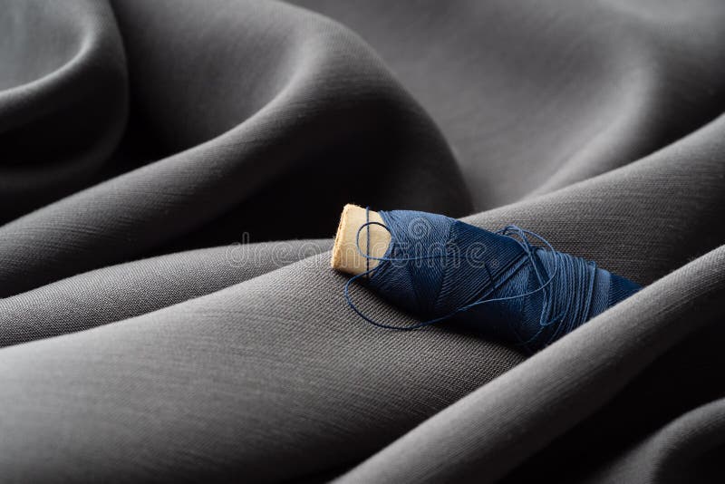 A Reel with Blue Threads in a Draped Soft Gray Fabric, Close-up, Macro ...