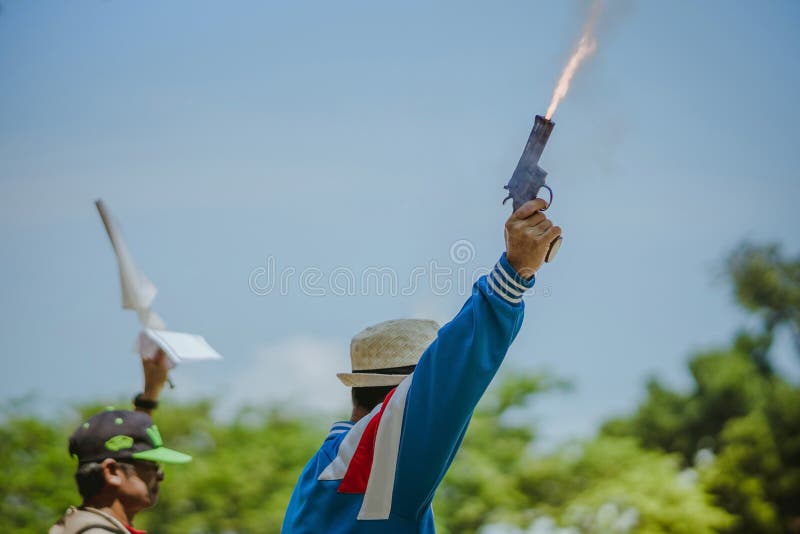 A Referee Fires the Starter Pistol for the Runners of a Track Ra ...