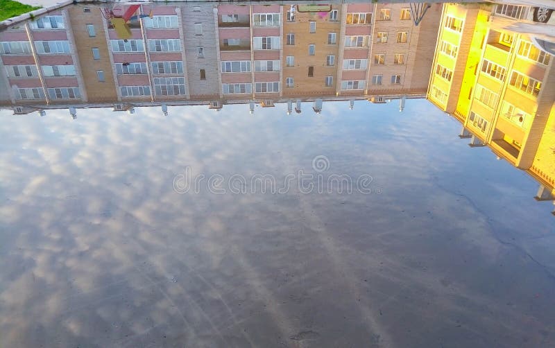 Reflection of the Building and the Sky in a Large Puddle of Water in ...