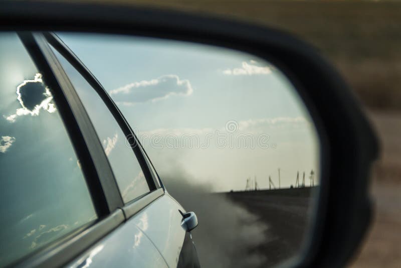 Reflection of a Car in the Rearview Mirror. Dust Behind the Car in the ...