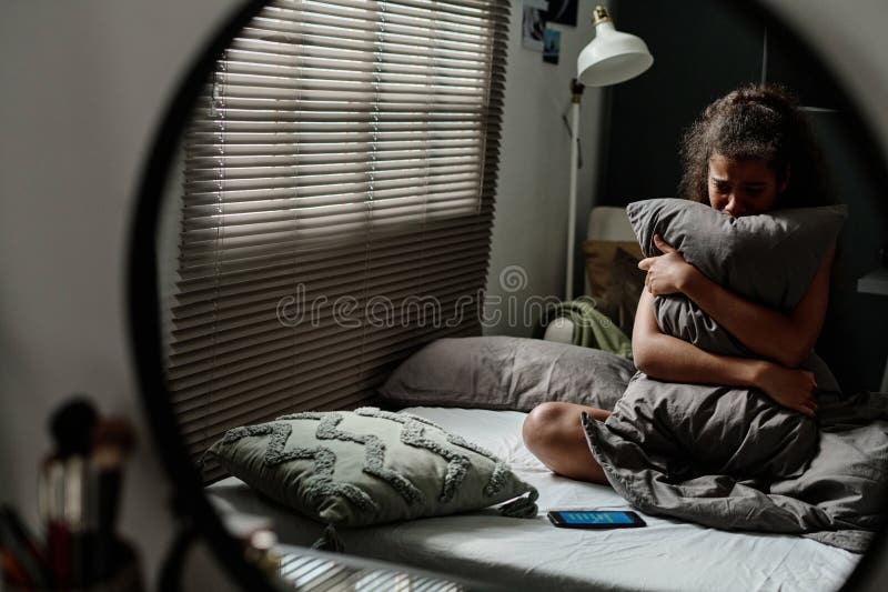 Reflection in Mirror of Crying Teenager with Pillow Sitting on Double ...