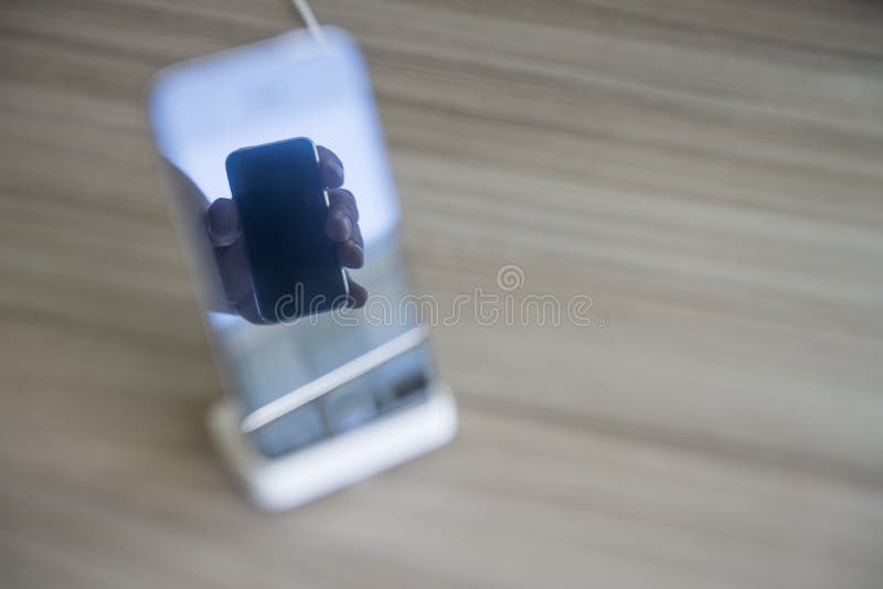 Reflection of a Mobile Phone on a Reflective Glass of Another Mobile ...