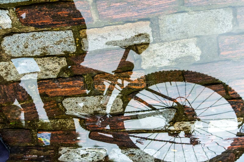 Reflection of Person and Bicycle in a Puddle of Rainwater in the River ...