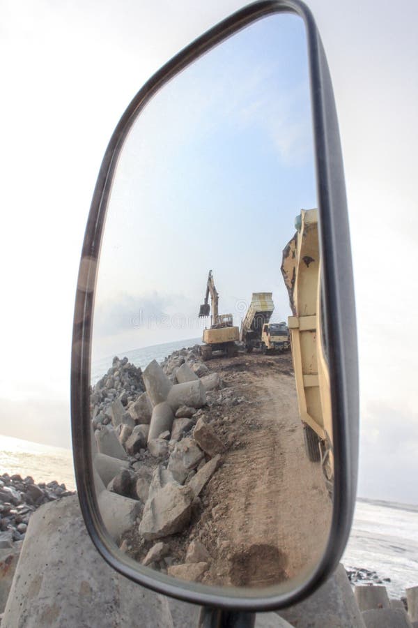 Reflection of Heavy Machinery at Coastal Wave Breaker Construction Area ...