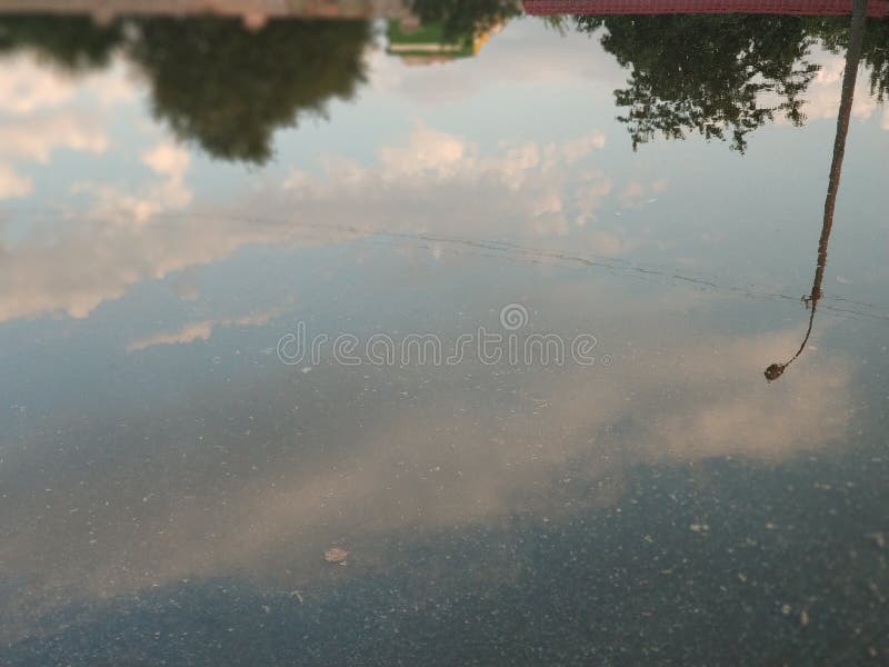 Reflection of the Sky and Clouds in a Puddle on the Asphalt Stock Photo ...
