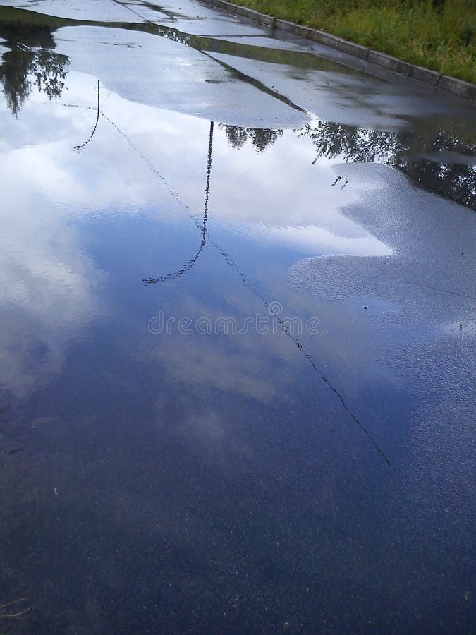 Reflection of the Sky and Lanterns in a Puddle on an Asphalt Road after ...