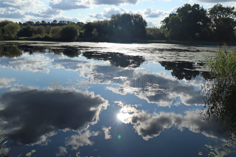 A Reflection of the Sun Passing Behind Some Black Clouds on the River ...
