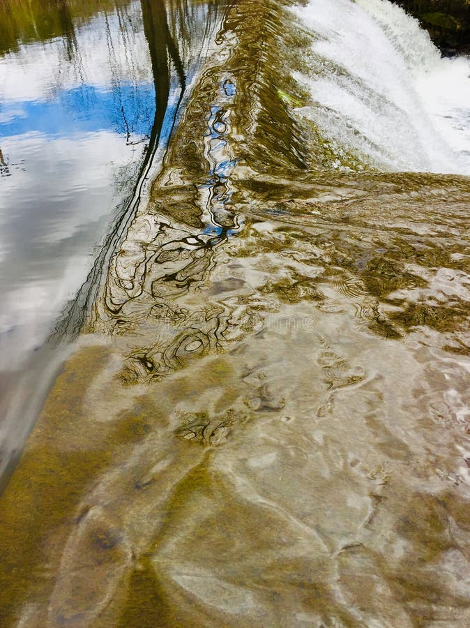 Reflection of Tree, Clouds in Water with Water Running Over Falls Stock ...