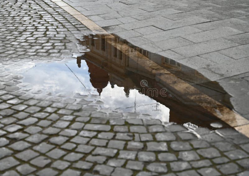 Reflections of Historic Architecture in a Puddle on Cobblestone Street ...