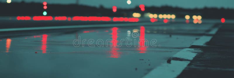 Reflections of a Runway Illuminated by Lights and Rain Puddles at Dusk ...