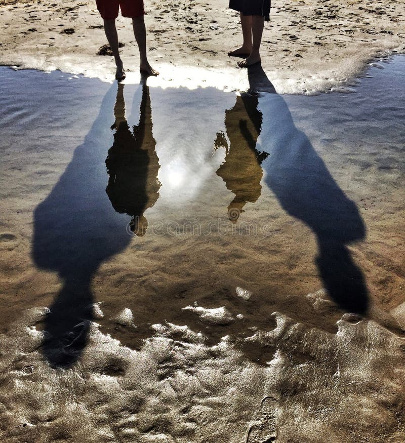 Reflections and Tall Shadows at the Beach Stock Photo - Image of stand ...