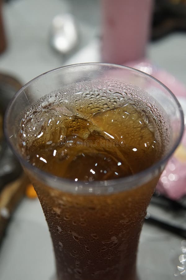 A Glass of Tea with Ice Sits on a Table, Reflecting Light and ...