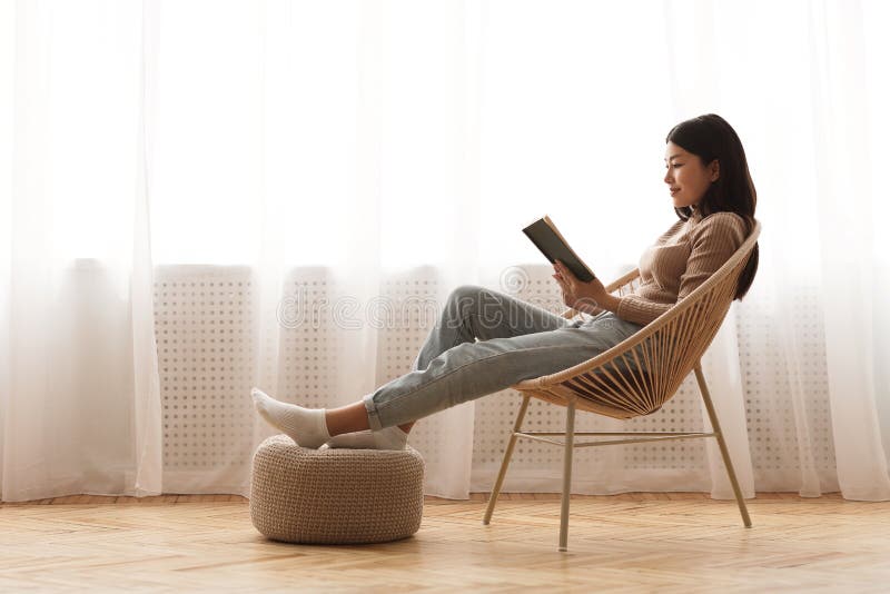 Relaxed Girl Reading Book Sitting In Chair By The Window Stock Image