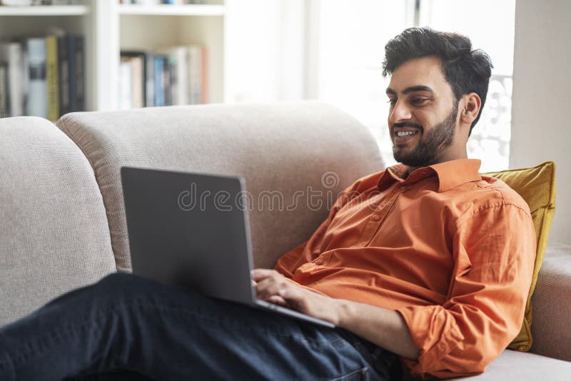 Middle Eastern Man Chilling on Couch at Home, Using Laptop Stock Photo ...