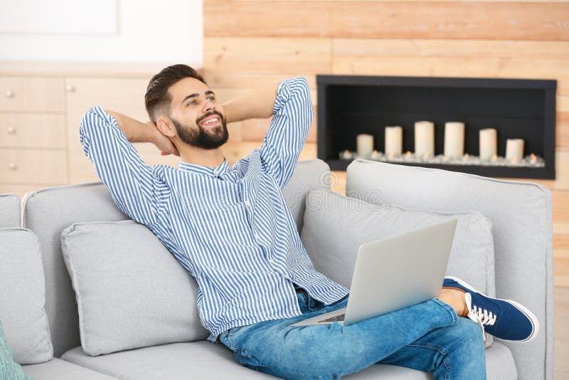Relaxed Handsome Young Man with Laptop on Sofa. Taking Break during ...