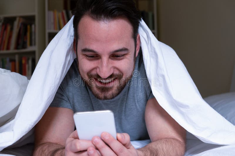 Cheerful Man Watching Cellphone Display in Bed Stock Image - Image of ...