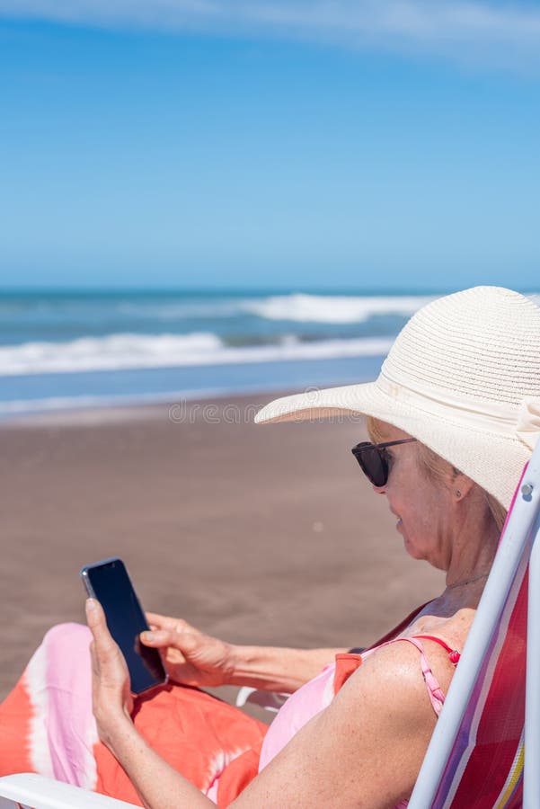 Relaxed Mature Woman Using a Mobile Phone at the Beach. Summer and ...