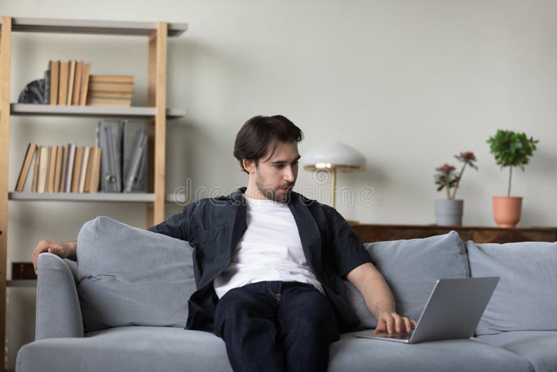 Relaxed Millennial Laptop User Guy Resting on Couch, Watching Movie ...