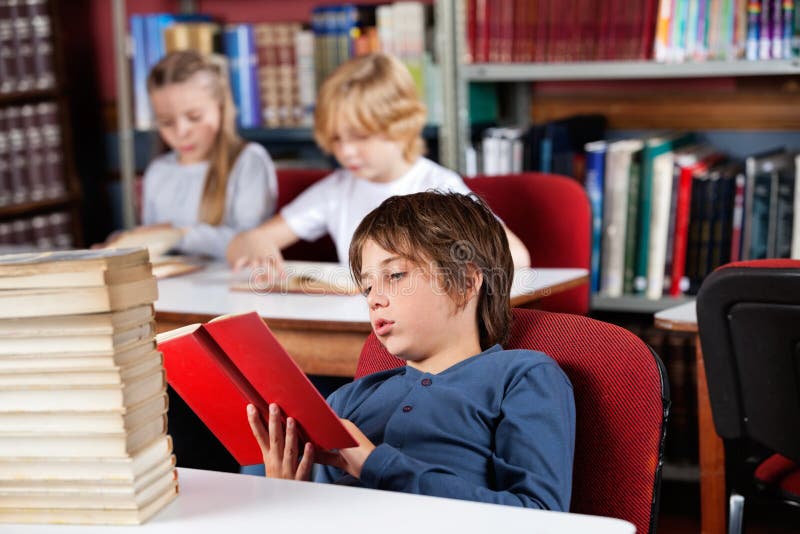 Relaxed Boy Reading Book at Table in Library Stock Image - Image of ...
