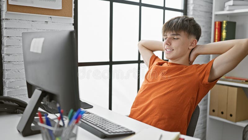 A Relaxed Teen Boy Takes a Break at His Desk with a Computer in a ...
