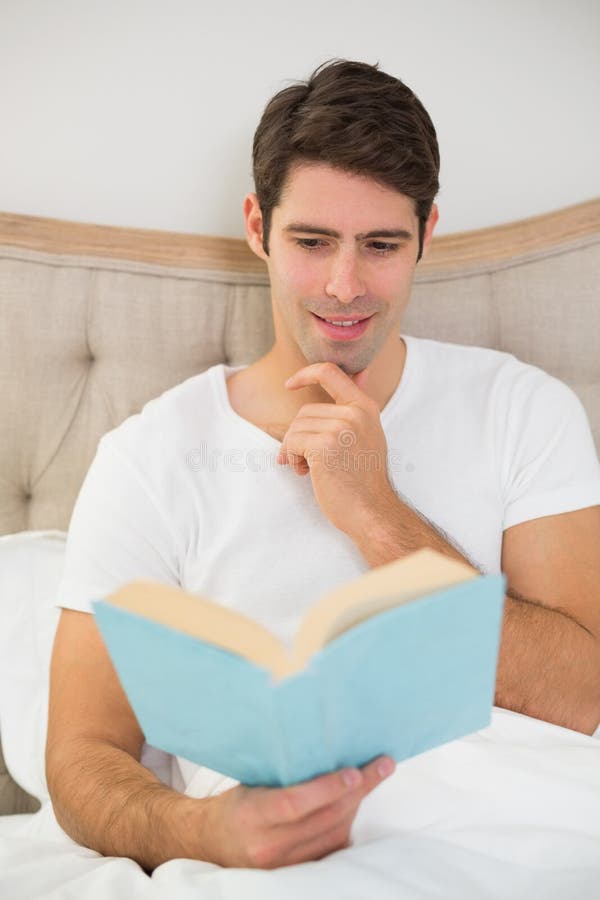 Relaxed Young Man Reading Book in Bed Stock Image - Image of relaxation ...