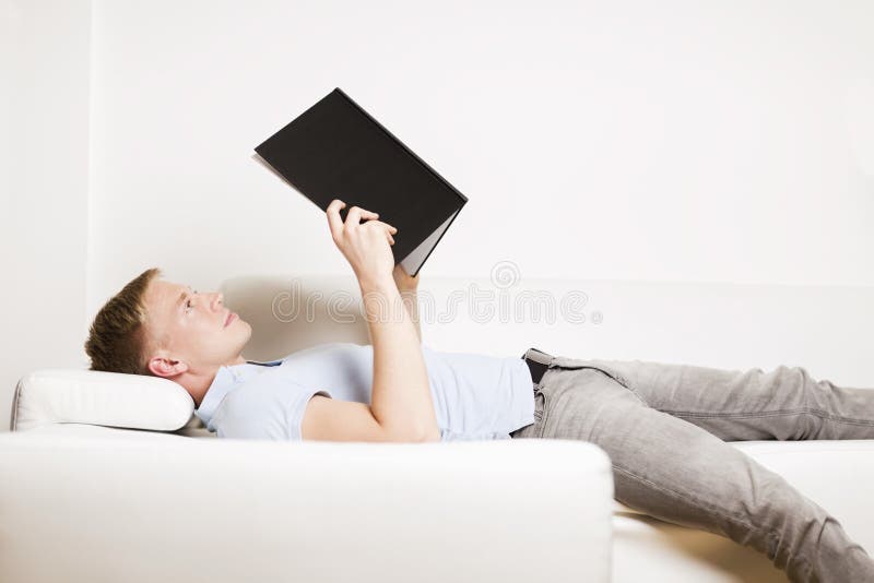 Relaxed Young Man Reading a Book and Lying on Sofa. Stock Photo - Image ...