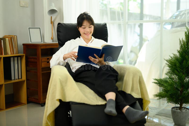 Relaxed Young Woman Reading a Book on a Comfortable Armchair Stock ...