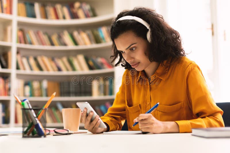 Remote Learning. Lady in Wireless Headphones Sitting at Desk in Library ...