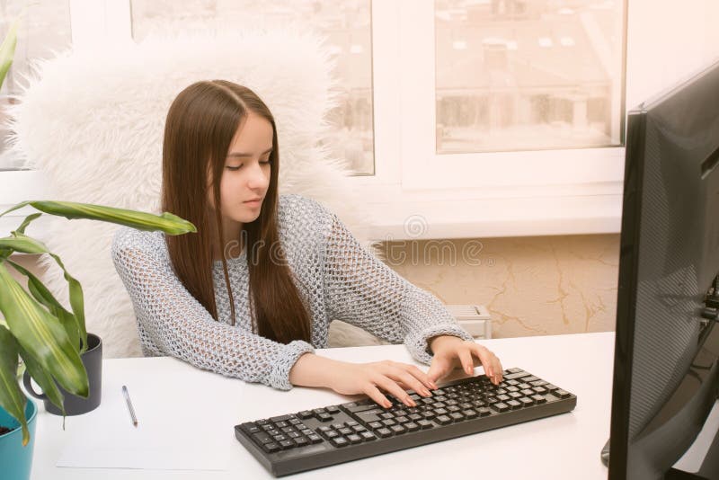 Remote Work. Young Girl Sits at a Table, Typing on a Computer, Smiling ...