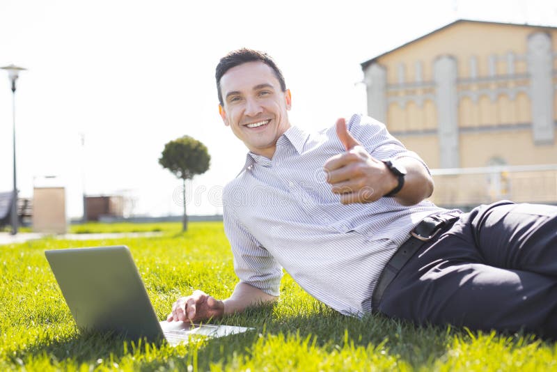 Experienced Remote Worker Using His Laptop Lying on the Grass Stock ...