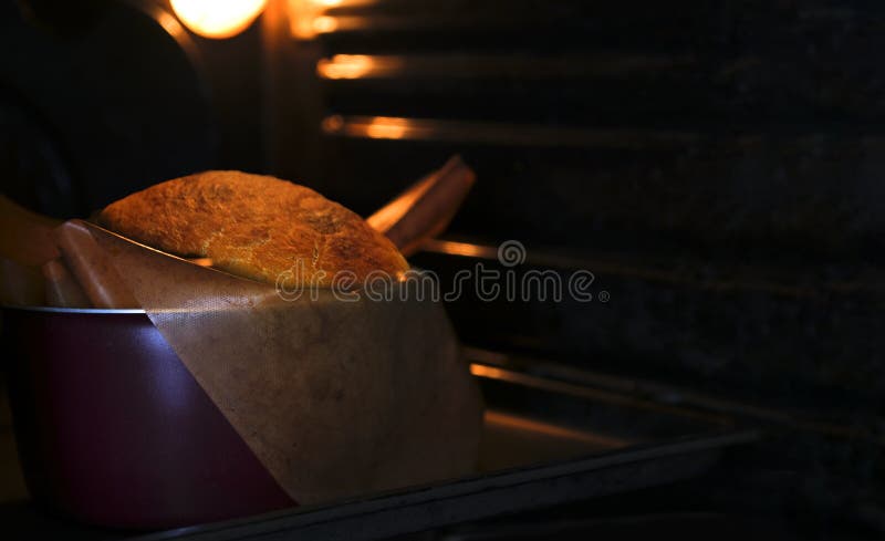 Removing a Home-made Loaf of Bread from the Oven in the Kitchen Stock ...