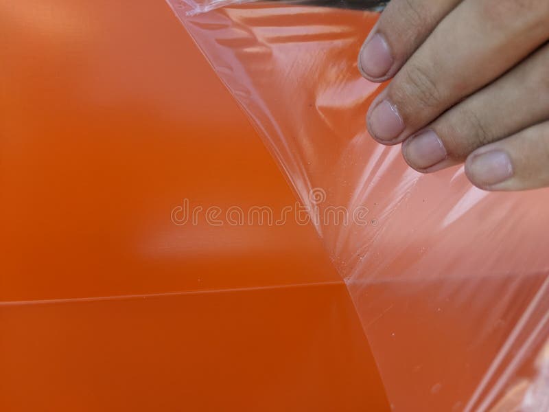 Removing the Packaging Film from the Orange Surface. Stock Photo ...