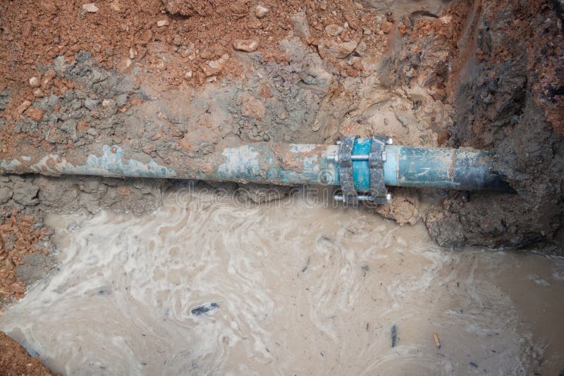 Broken Pipe in Hole with Water Motion at Roadside and Plumber Working ...