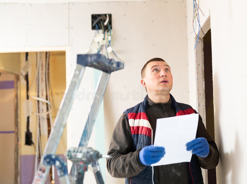 Repair Man Planning His Work in Apartment and Checking Documentation ...