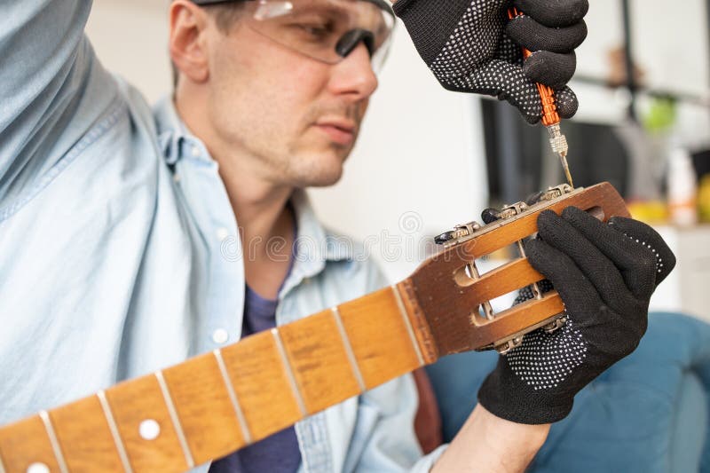 Repair of an Old Guitar. the Man Inserts the Strings into the Holes in ...