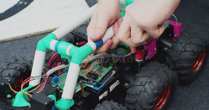 Repairing a Small Robot on Wheels with a Screwdriver. Hands of a ...