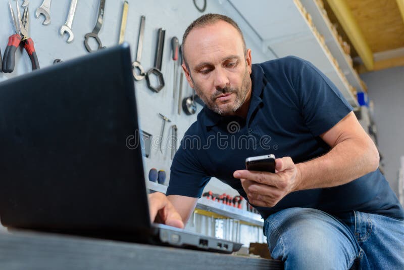 Repairman Checking Phone in Workshop Stock Photo - Image of plank ...