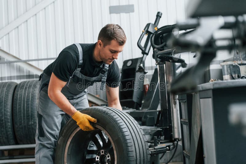 Replacement of the Old Tire. Man in Uniform is Working in the Auto ...
