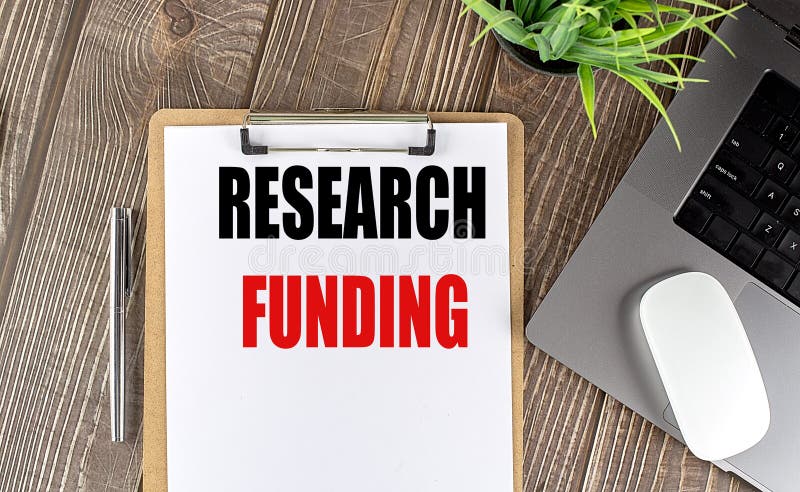 RESEARCH FUNDING Text on Clipboard Paper with Laptop, Mouse and Pen ...