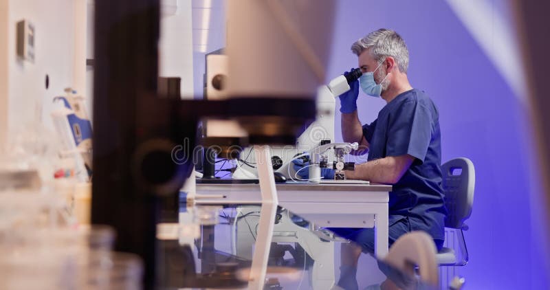 Research Male Scientist in Protective Mask Analyzing a Sample, Looking ...
