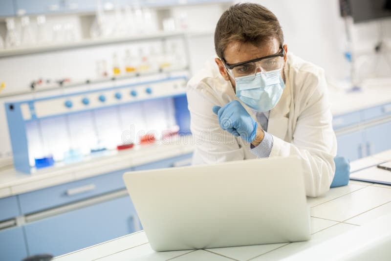 Researcher in White Lab Coat and Protective Mask Working Using Laptop ...