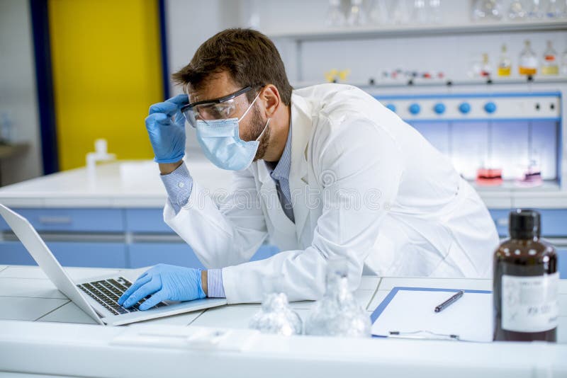 Researcher in White Lab Coat and Protective Mask Working Using Laptop ...