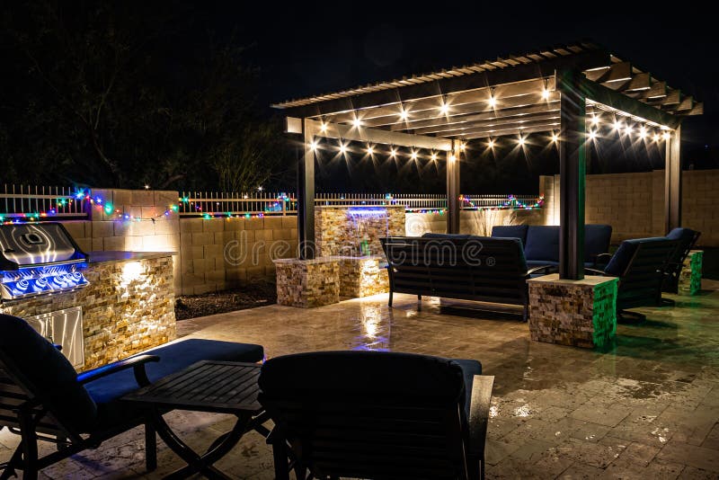 A Resort Style Backyard at Night with a Waterfall, Pergola, and a ...